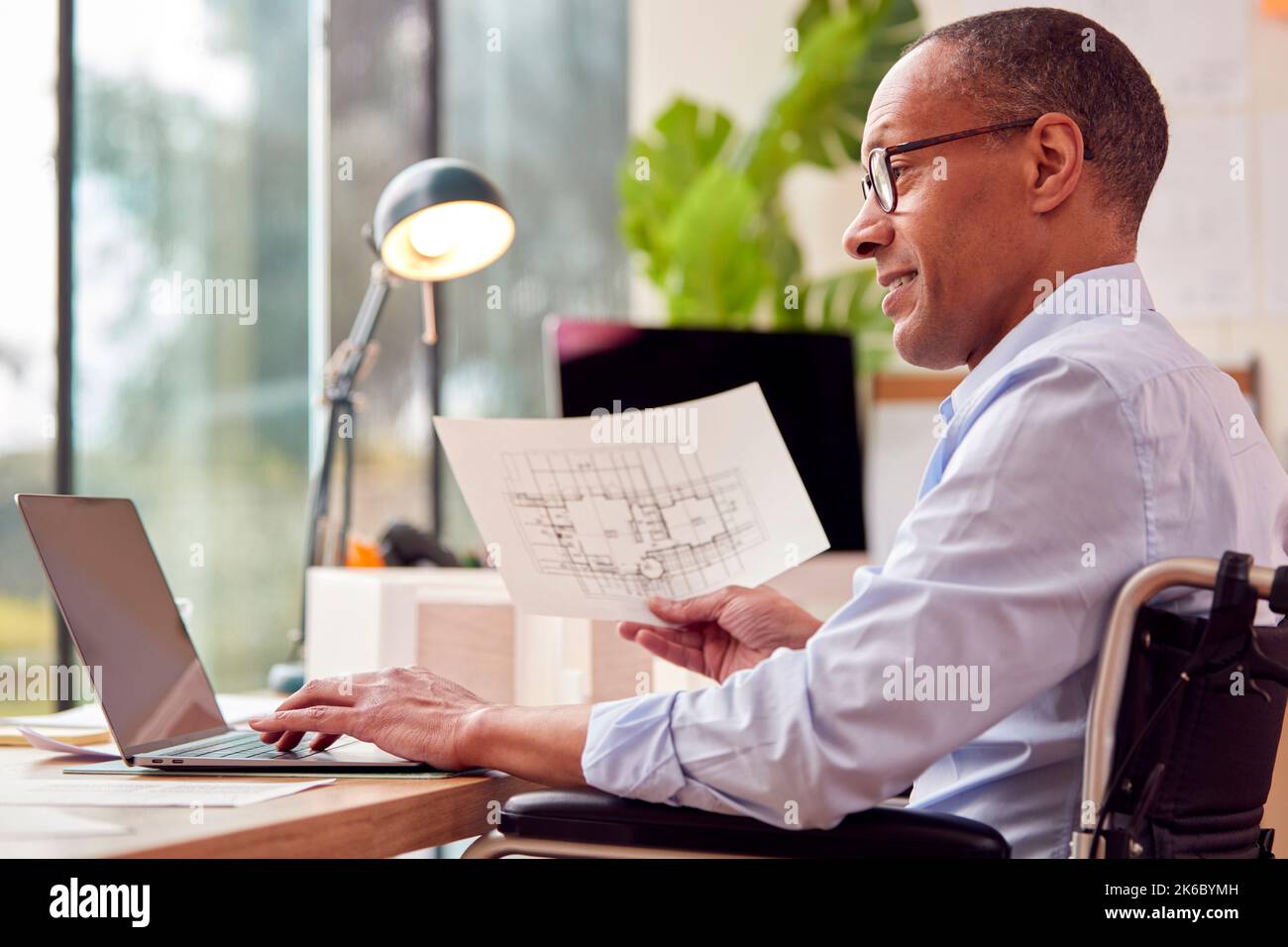 Mature Male Architect In Wheelchair Working In Office At Desk Studying ...