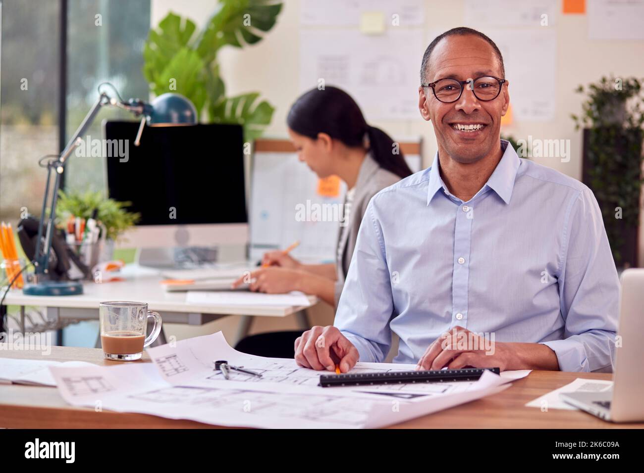Portrait Of Male And Female Architects Working In Office At Desks On ...