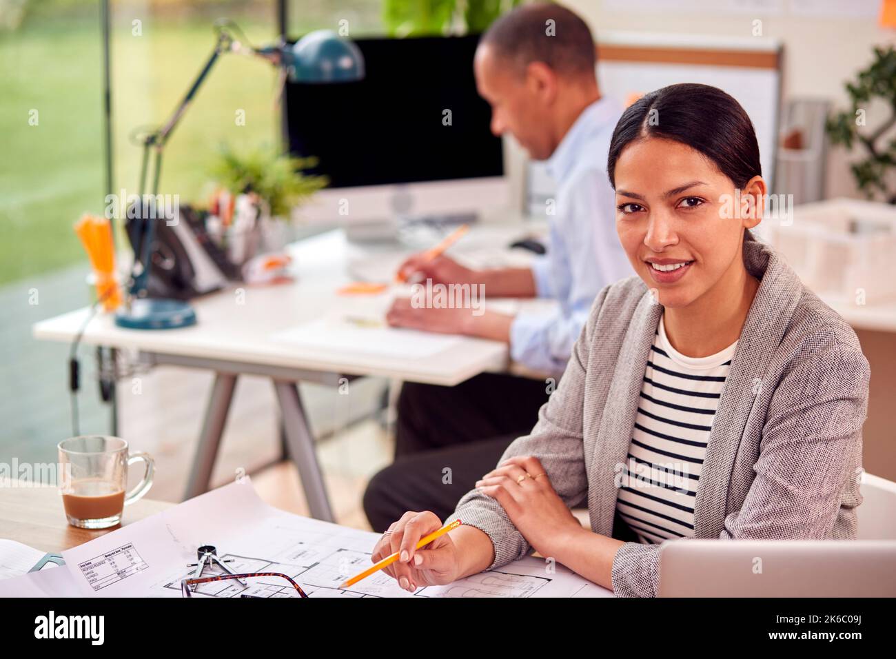 Portrait Of Male And Female Architects Working In Office At Desks On ...