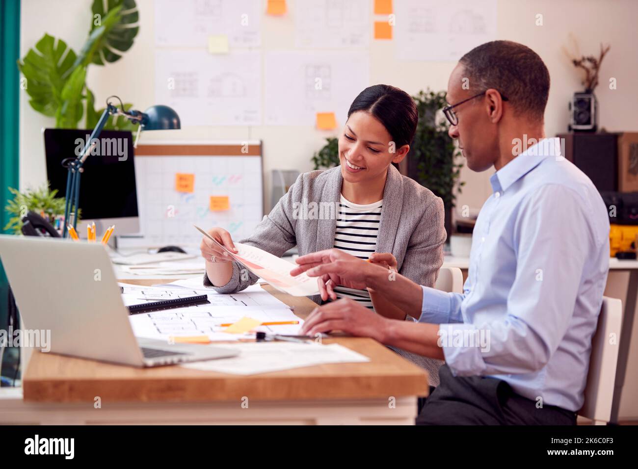 Male And Female Architects Or Interior Designers Working In Office On ...
