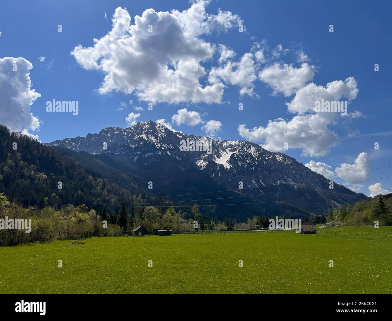A beautiful landscape of a tall snowy mountain over a green field Stock ...