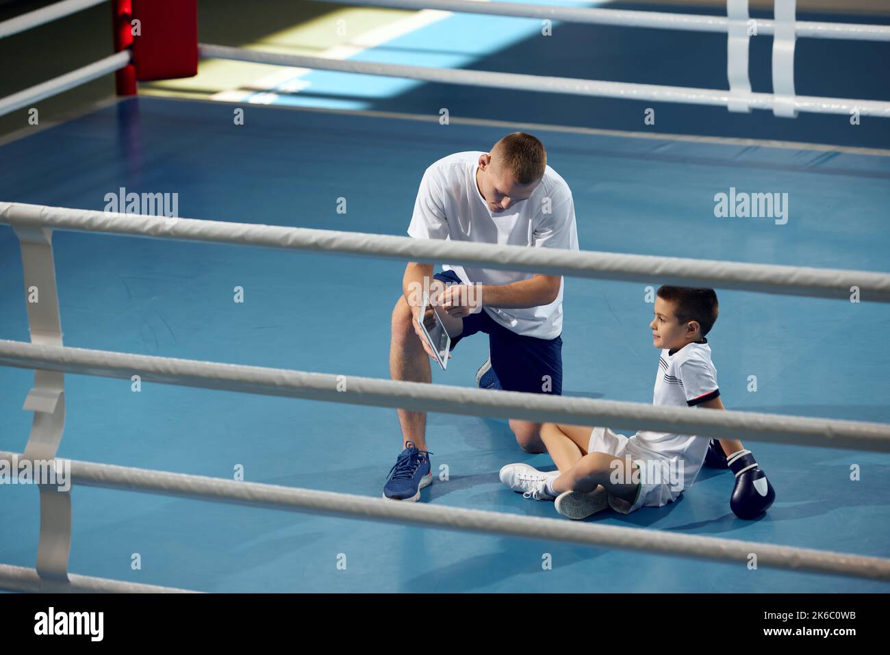 Two athletes, son and father is doing sports in gym. Beginner boxer ...