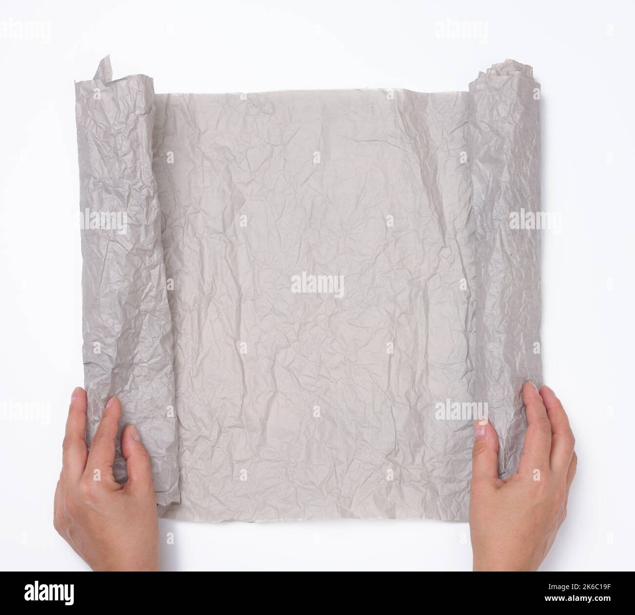 Two female hands hold an unwrapped roll of gray crumpled paper on a ...