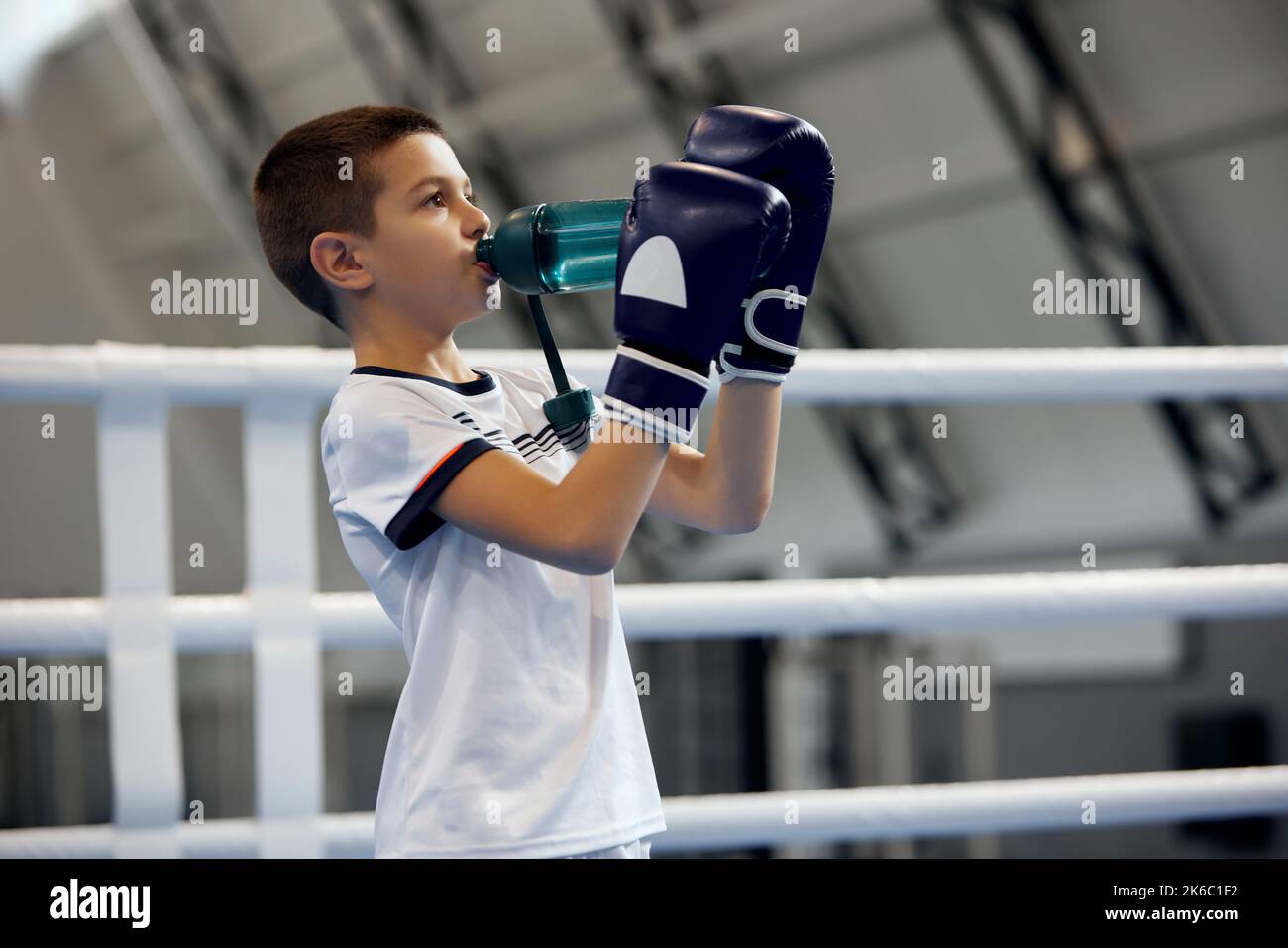 Keep water balance. Little boy, beginner boxer in sport uniform ...