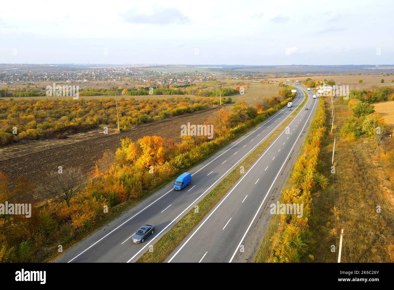 Highway, road in autumn in leaf fall. Cars drive on asphalt road ...