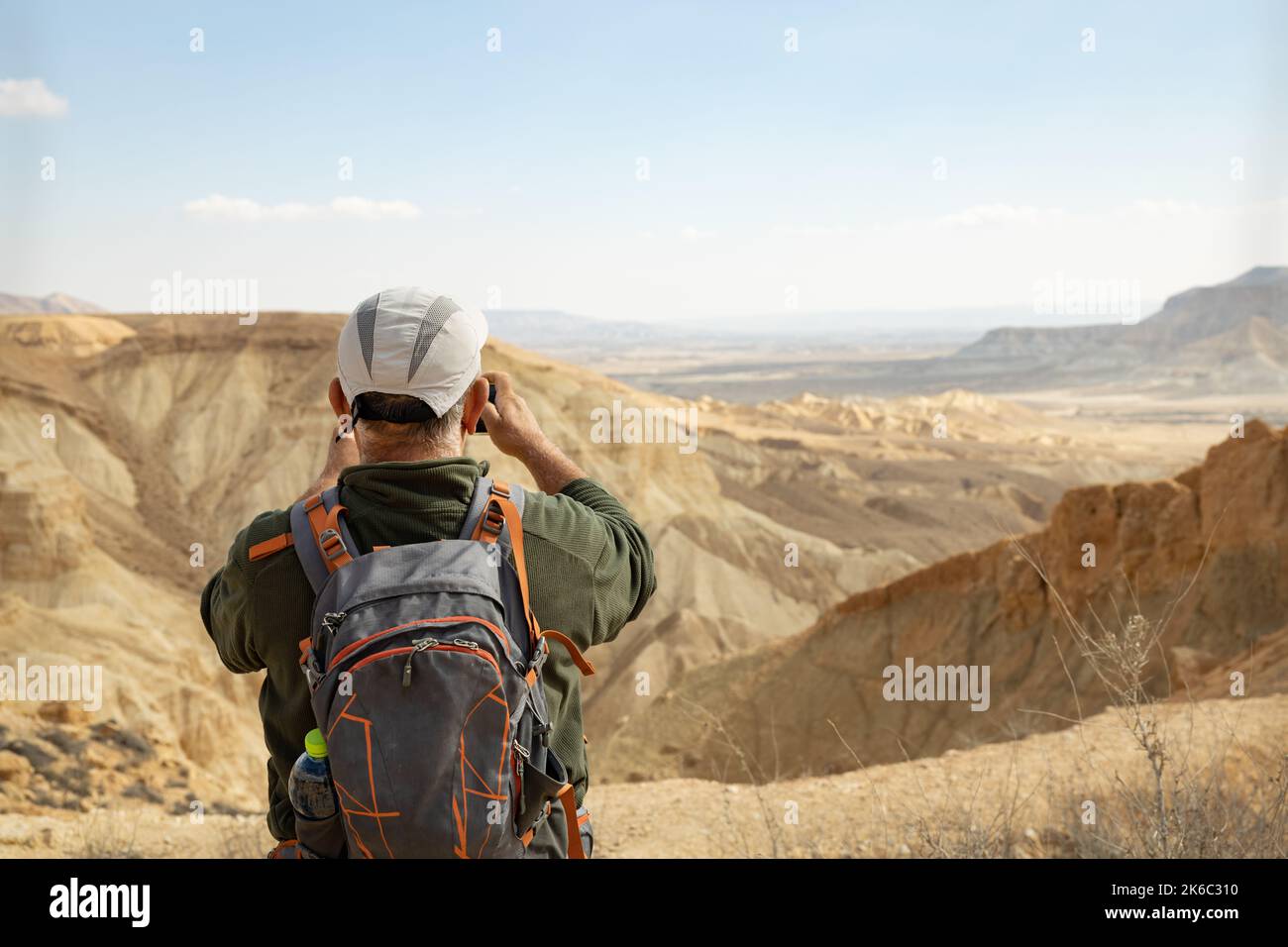backpacker photographing the desert scenery, Zin valley, Negev desert ...