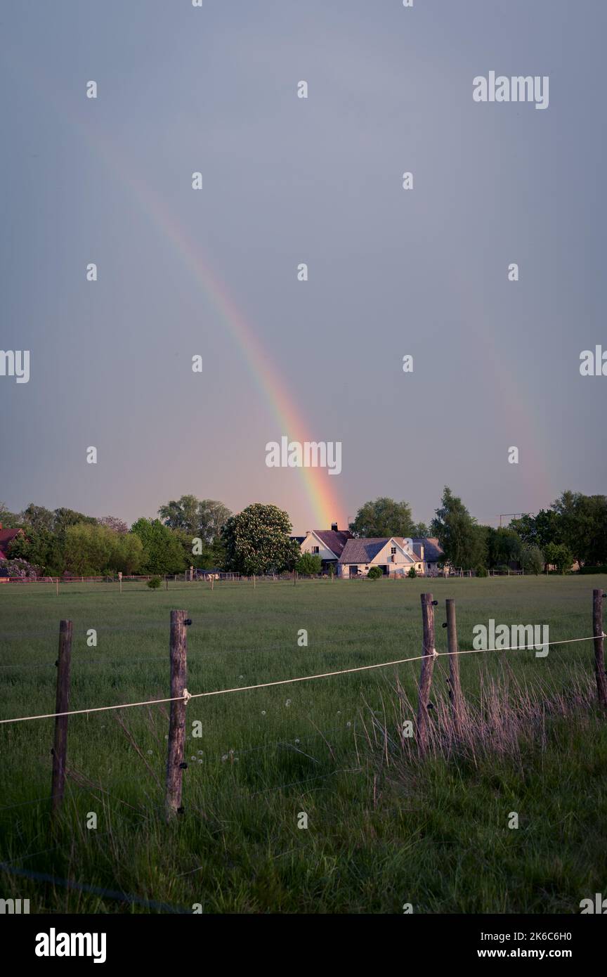 Rainbow ending at rural house in the countryside in Skåne (Scania ...