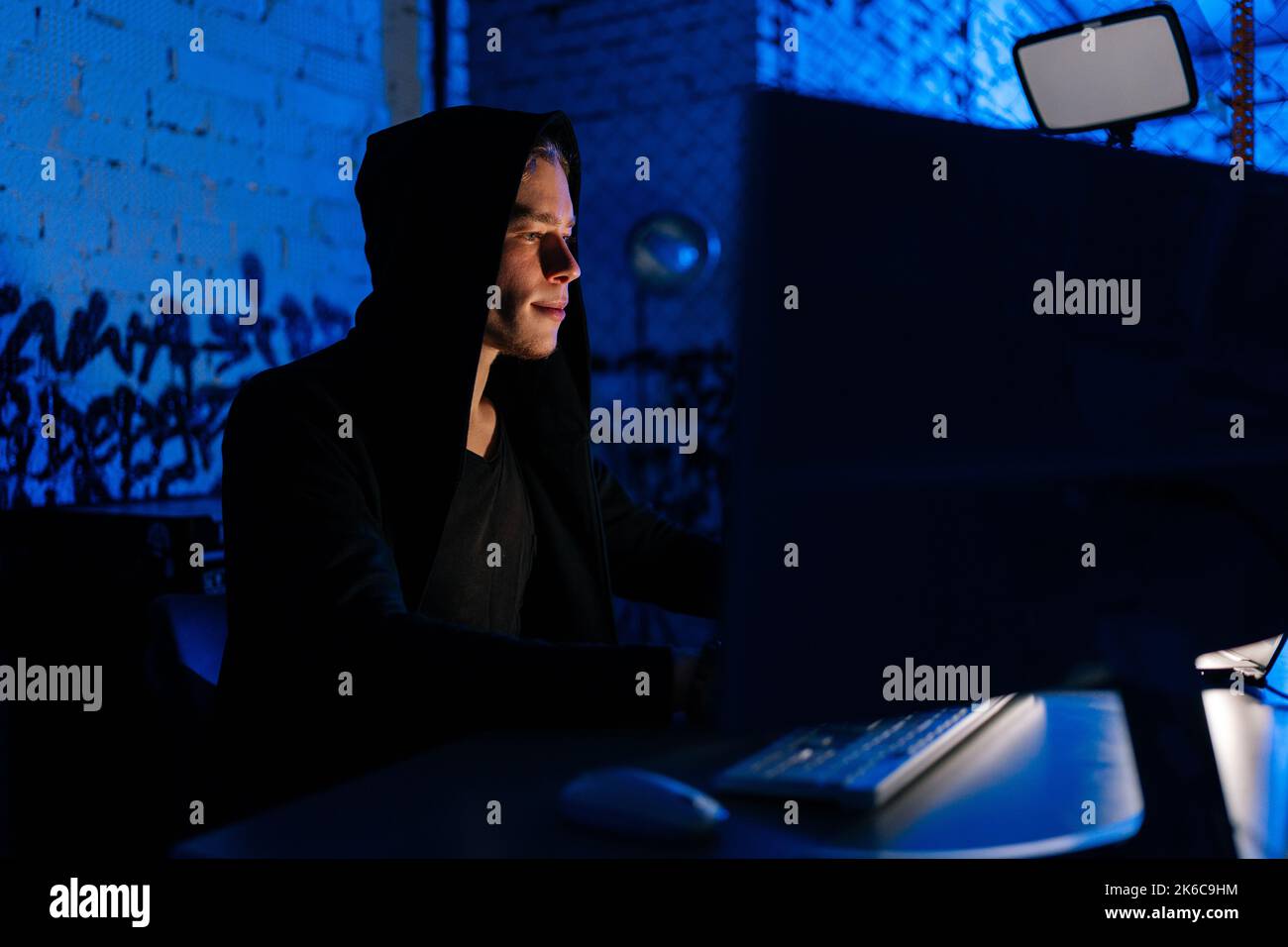 Side view of dangerous hacker male breaking into corporate data servers using laptop and ...