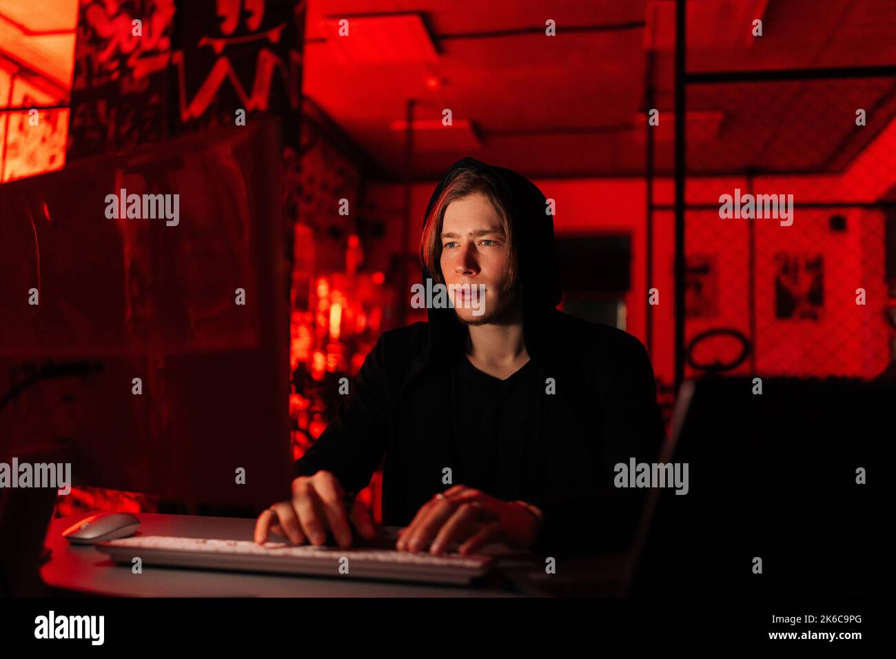 Front view of focused hacker man in black sweatshirt using laptop and ...