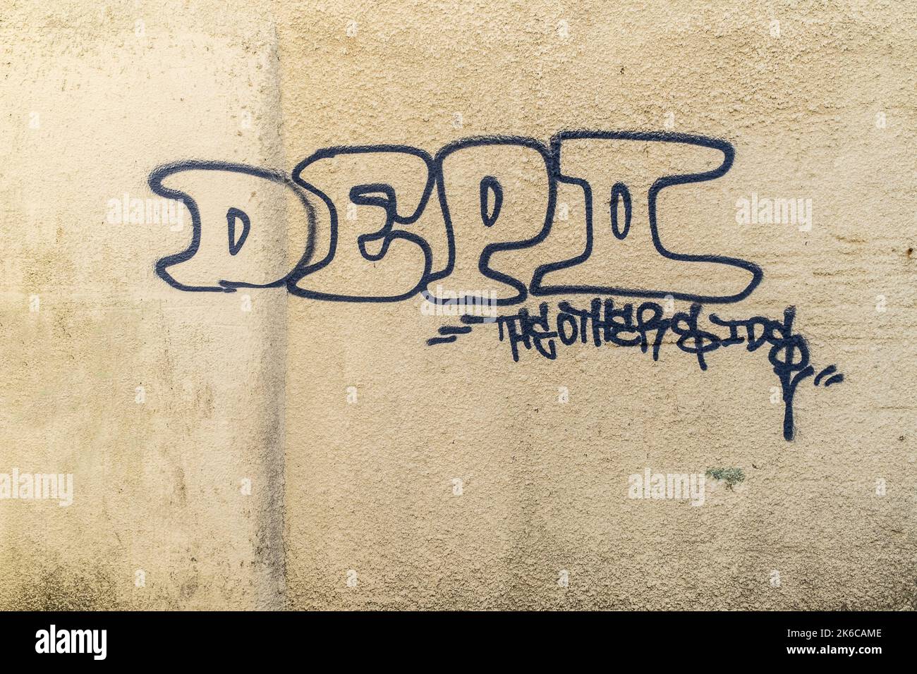 Ugly graffiti tag sprayed over a wall in an old alleyway called an Ope ...