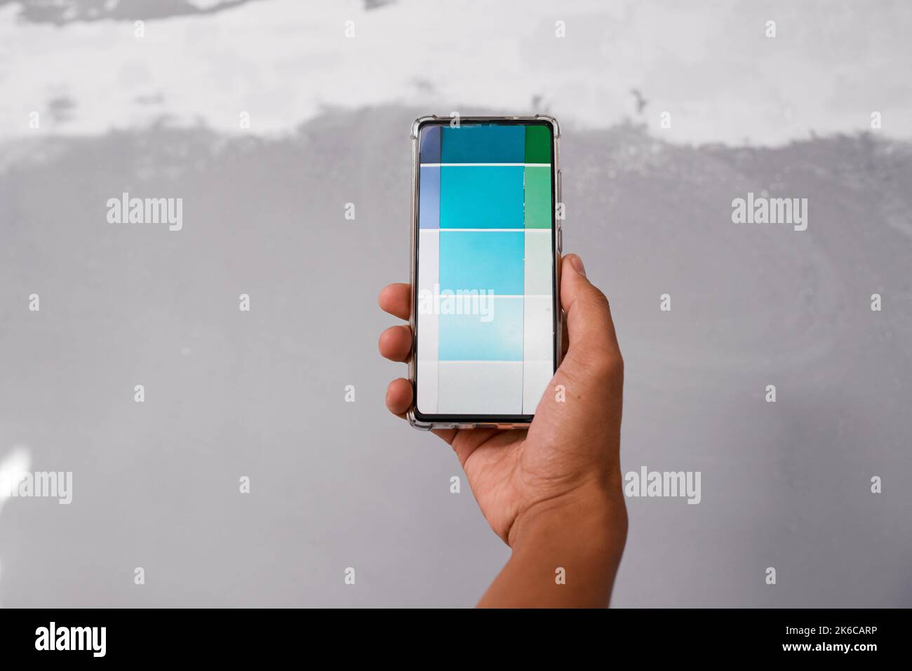 Close up of hand holding cellphone with digital paint swatch against ...