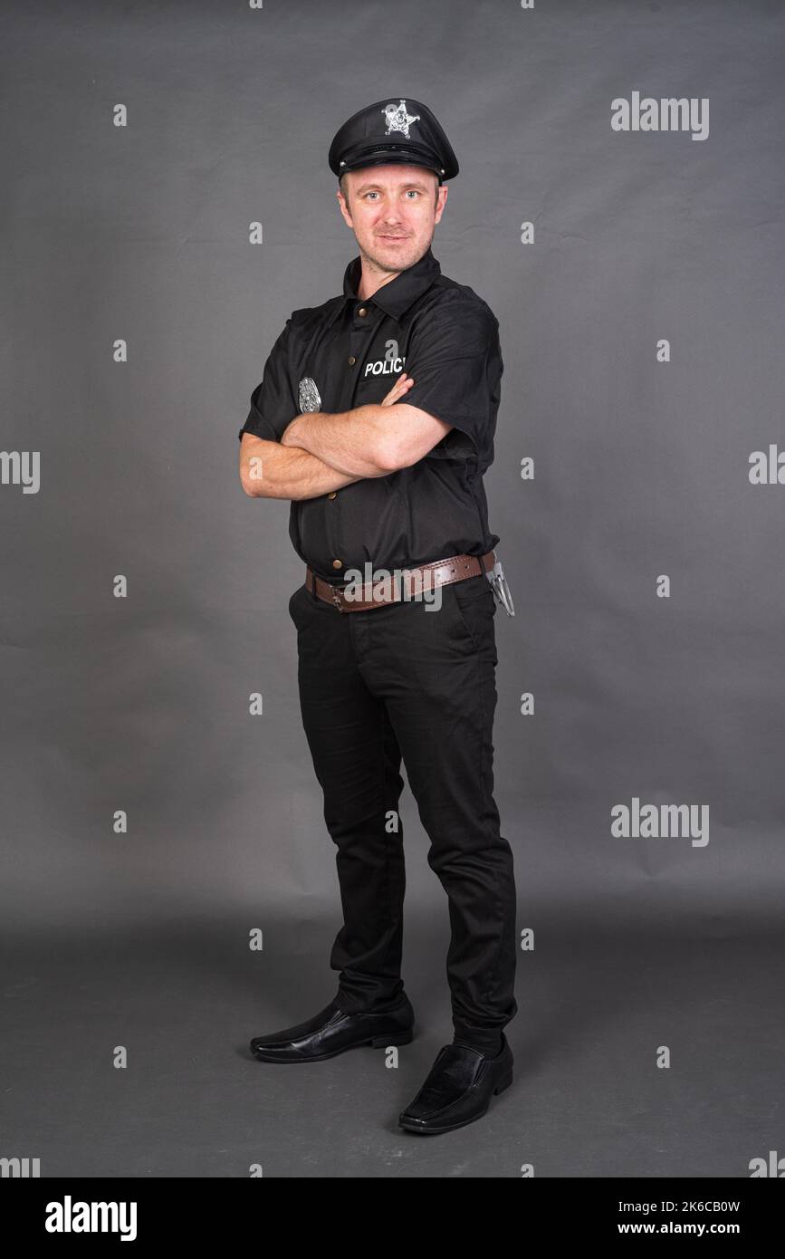 Portrait of Caucasian man wearing police uniform costume against gray ...