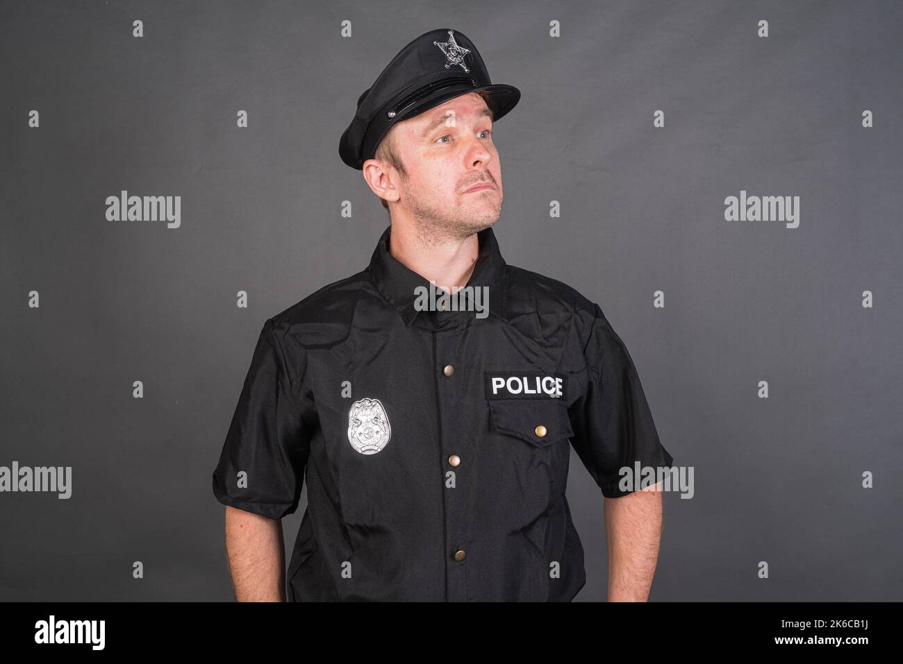 Portrait of Caucasian man wearing police uniform costume against gray ...