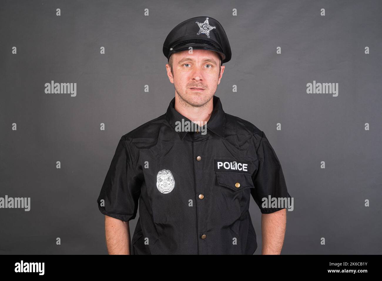 Portrait of Caucasian man wearing police uniform costume against gray ...