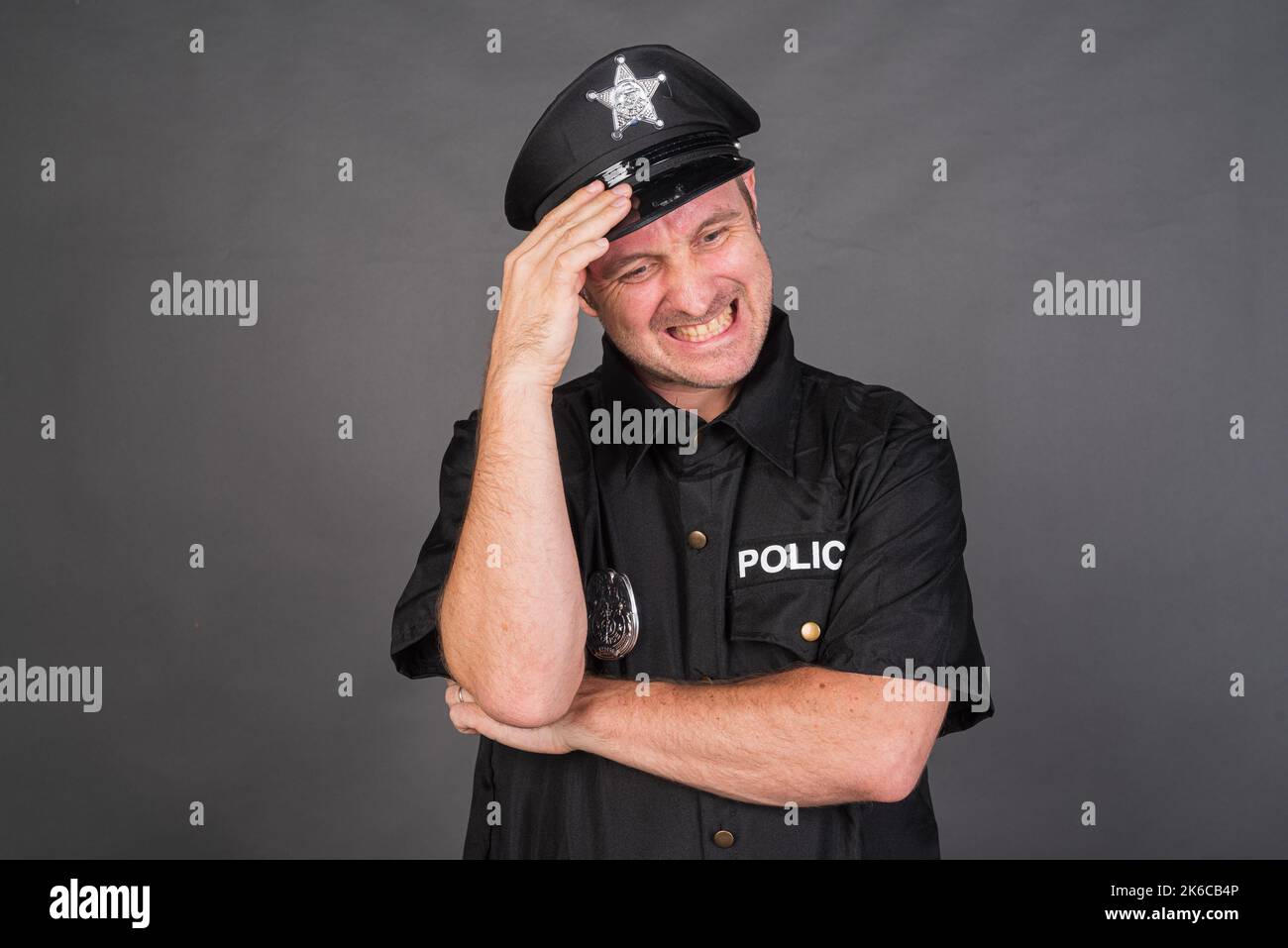 Frustrated Caucasian man wearing police uniform costume against gray ...