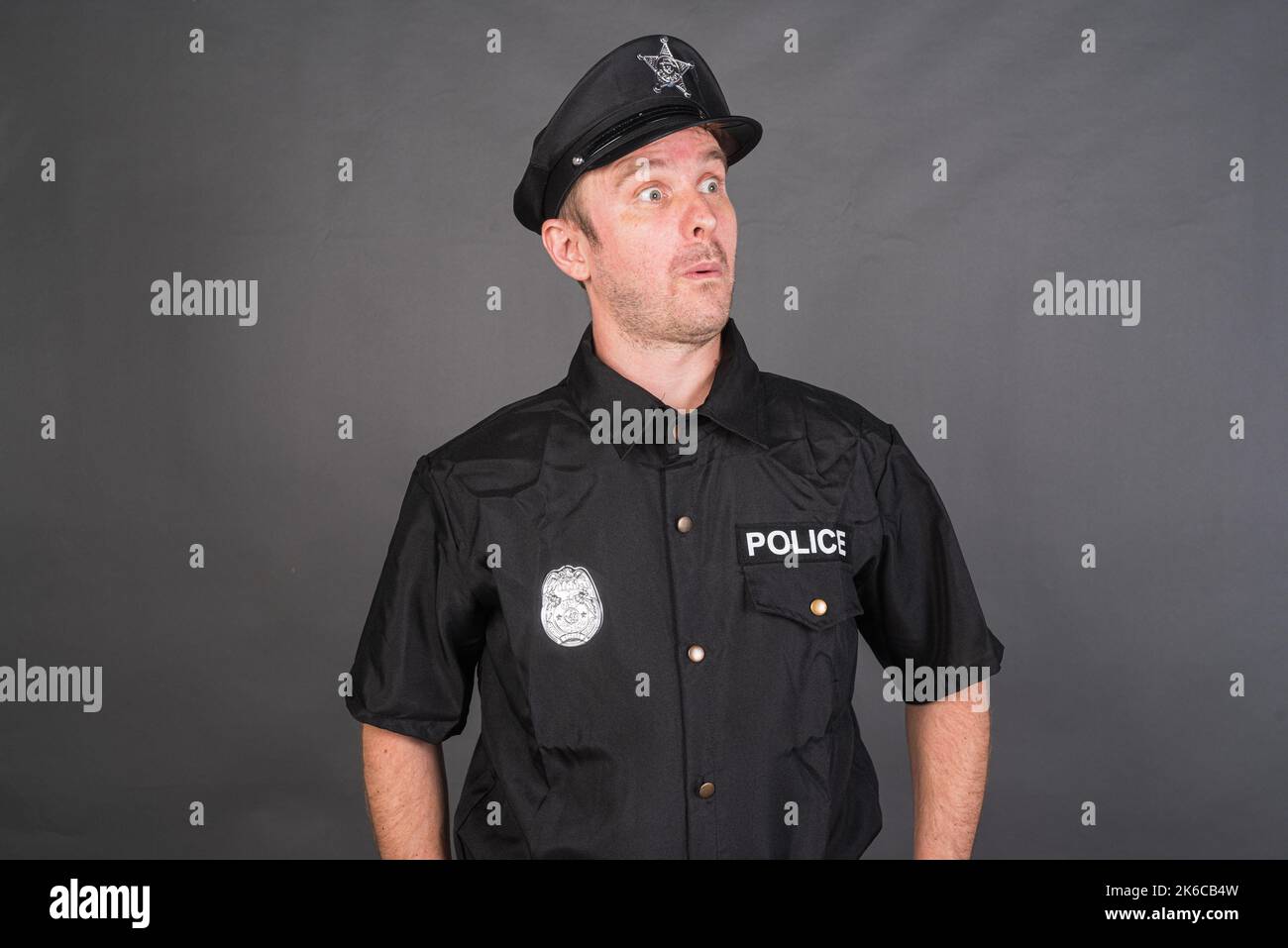 Portrait of Caucasian man wearing police uniform costume against gray ...