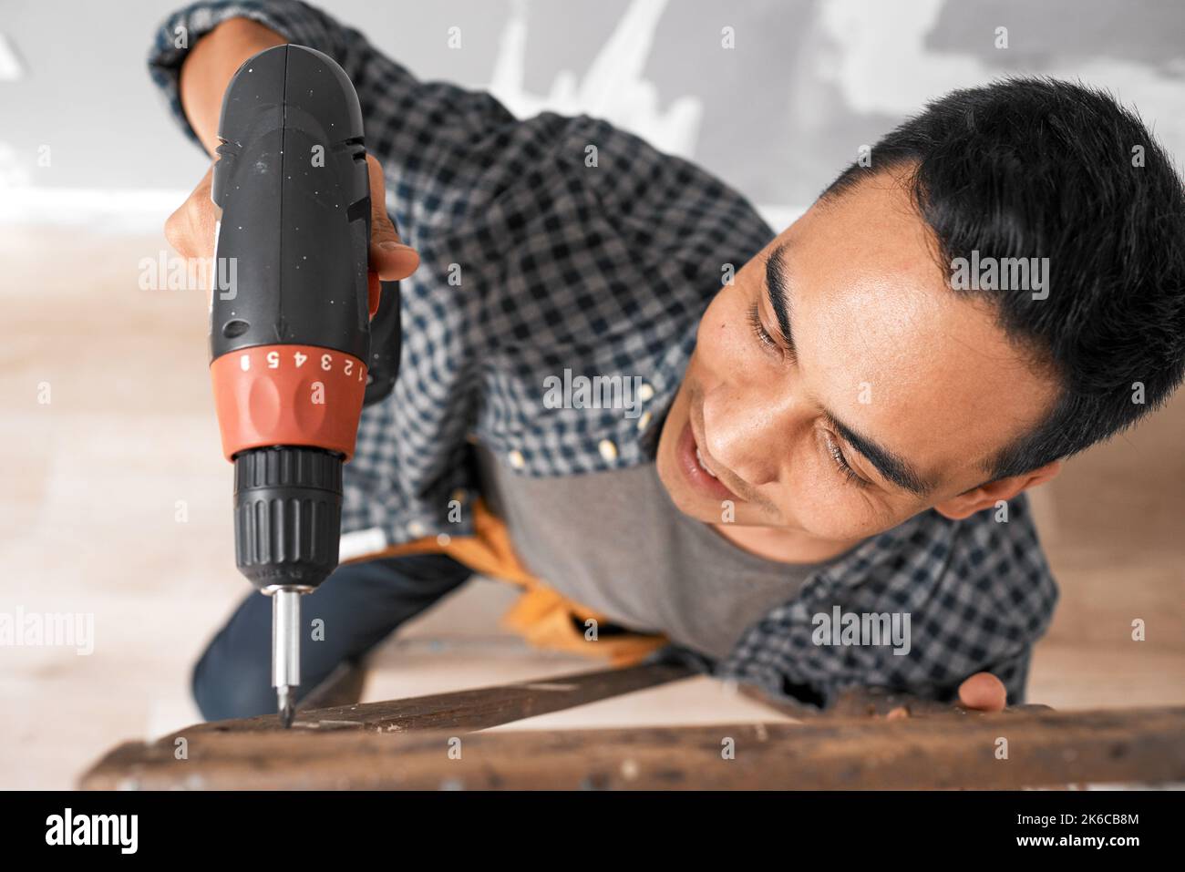 Overhead shot of young Asian man drilling into wood during home ...