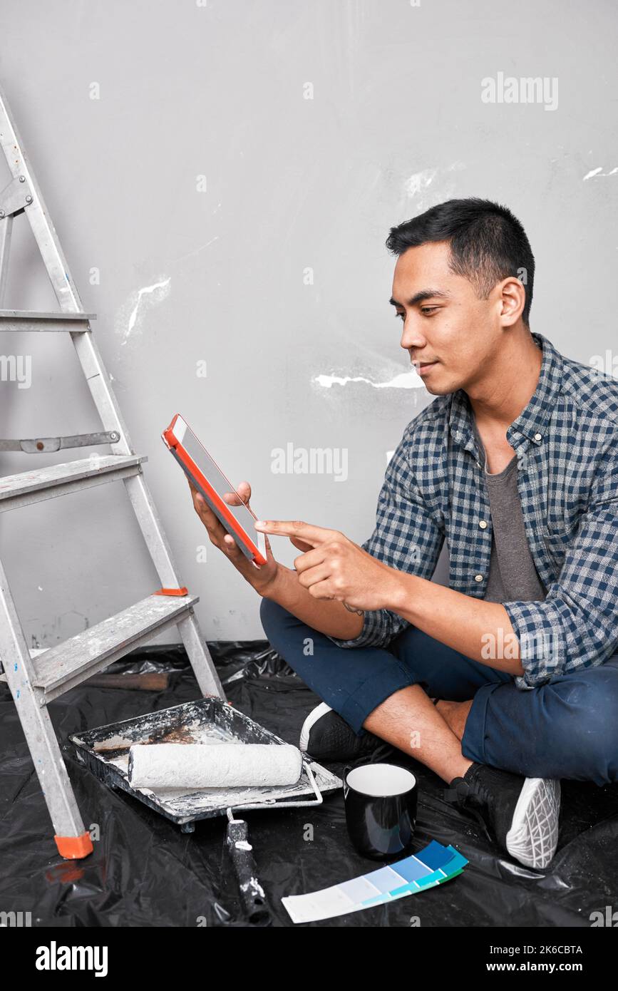 A young Asian man researches home DIY ideas and how-to guides while ...