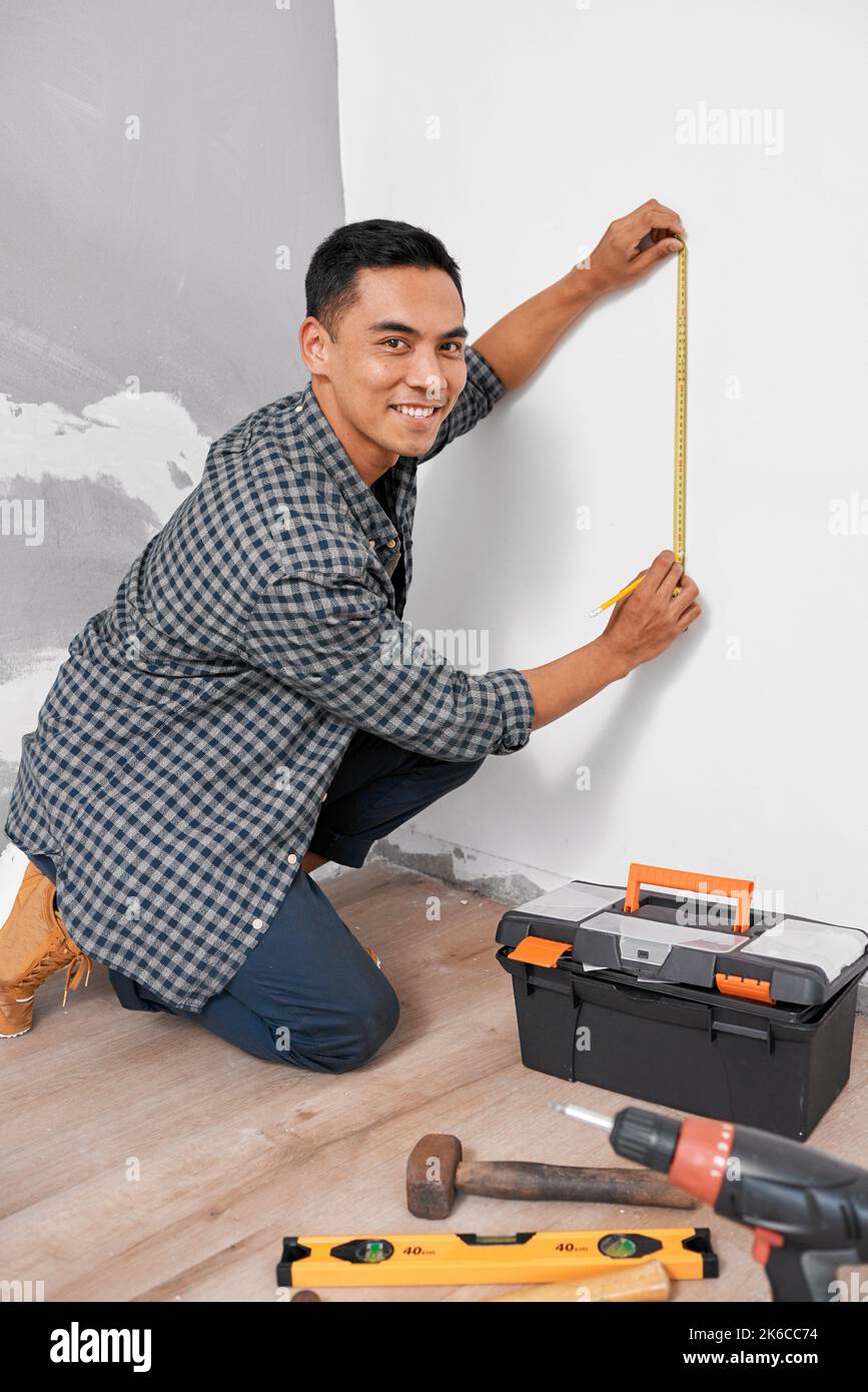 A young Asian man looks at the camera while measuring vertically for ...