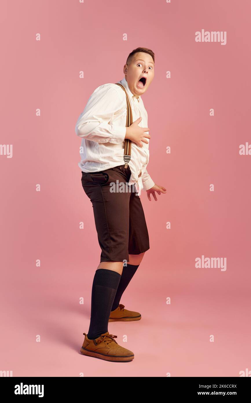 Fright, fear. Scared teen boy in white shirt and shorts with suspenders ...