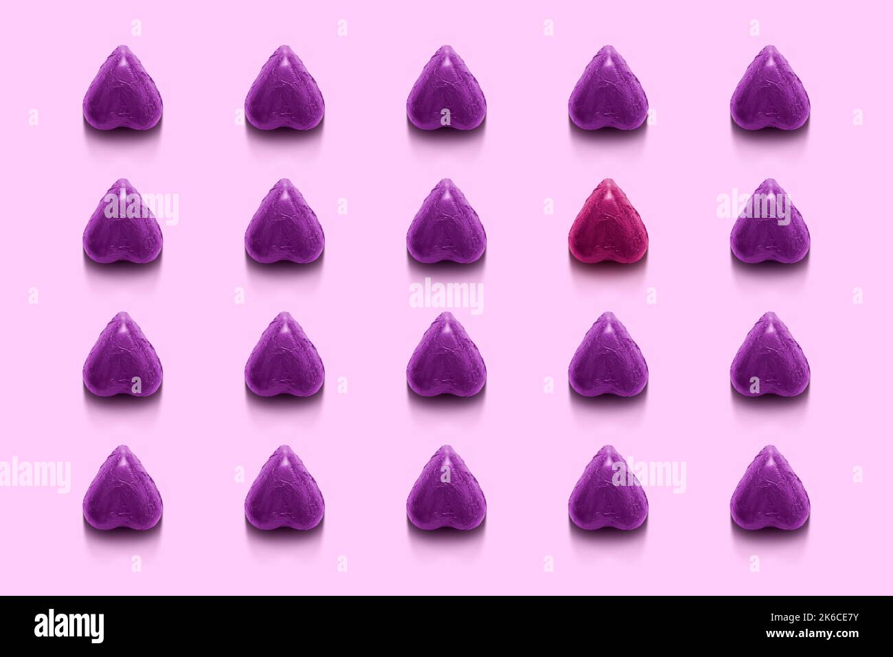 Pattern of heart shaped candies wrapped in foil with one red heart ...