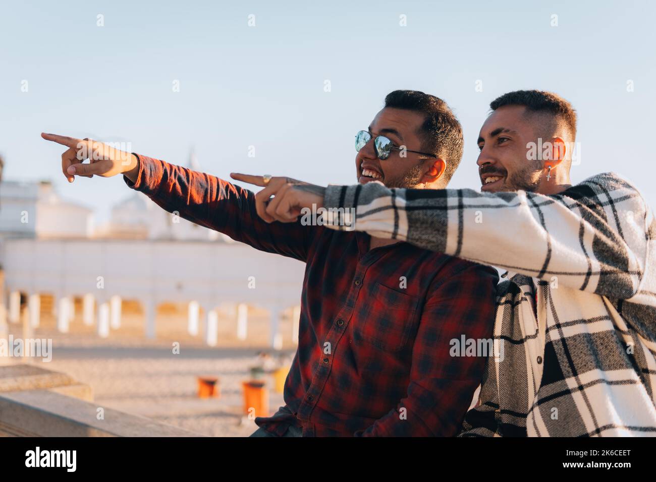 Two cool Caucasian males in checks shirts pointing by fingers with blur ...