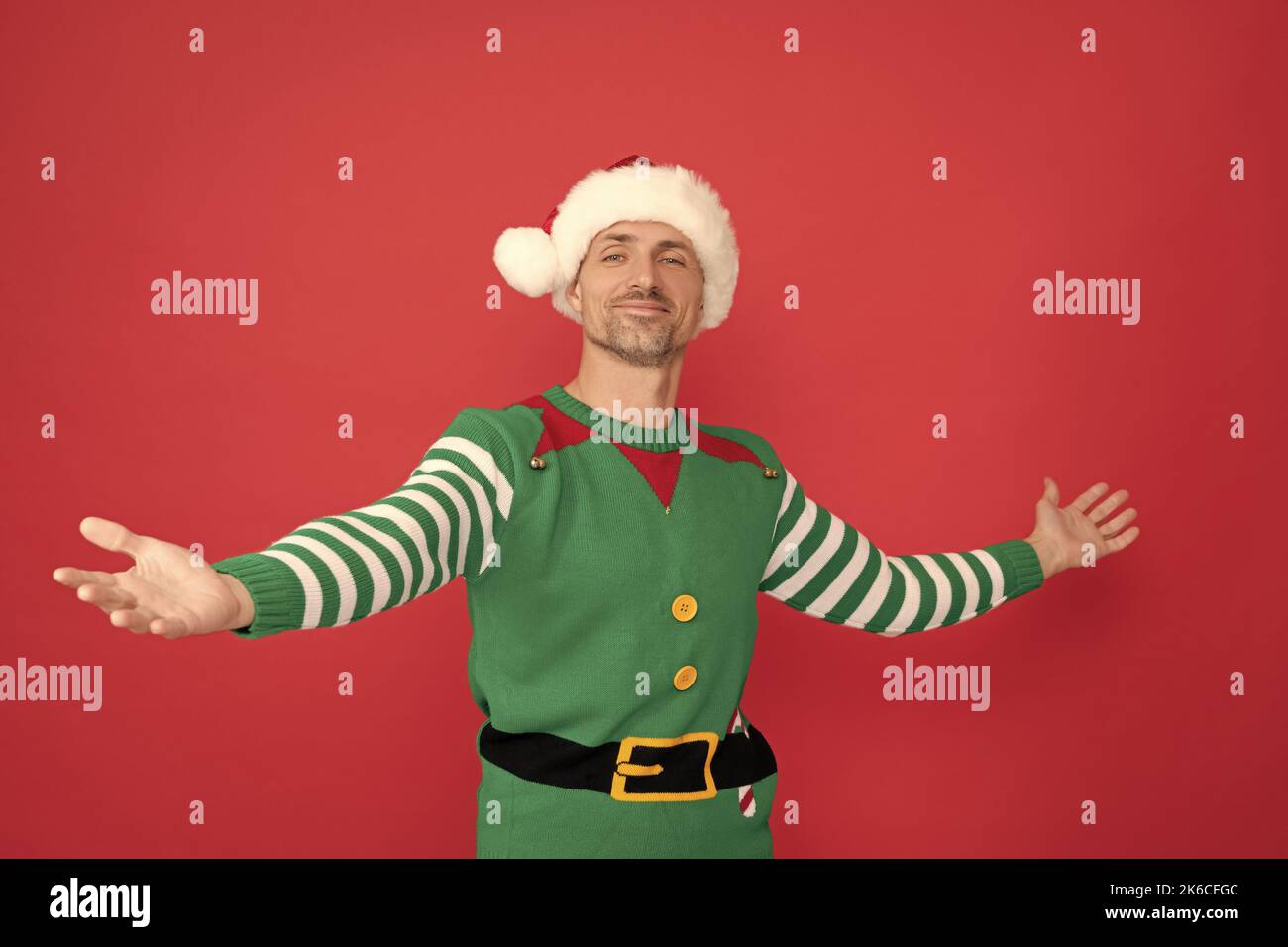 happy man in elf costume. xmas guy in santa claus hat on red background ...