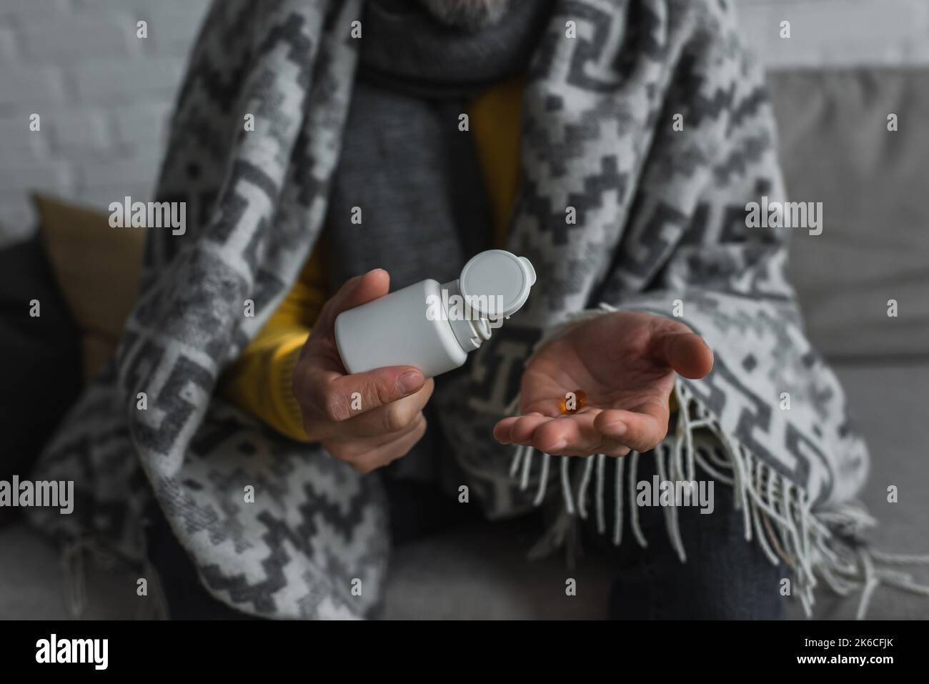 cropped view of diseased man under warm blanket holding container and ...