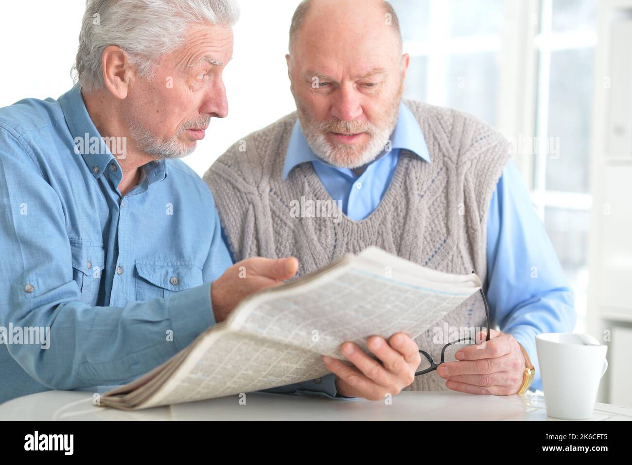 Portrait of two elderly people reading a newspaper Stock Photo - Alamy