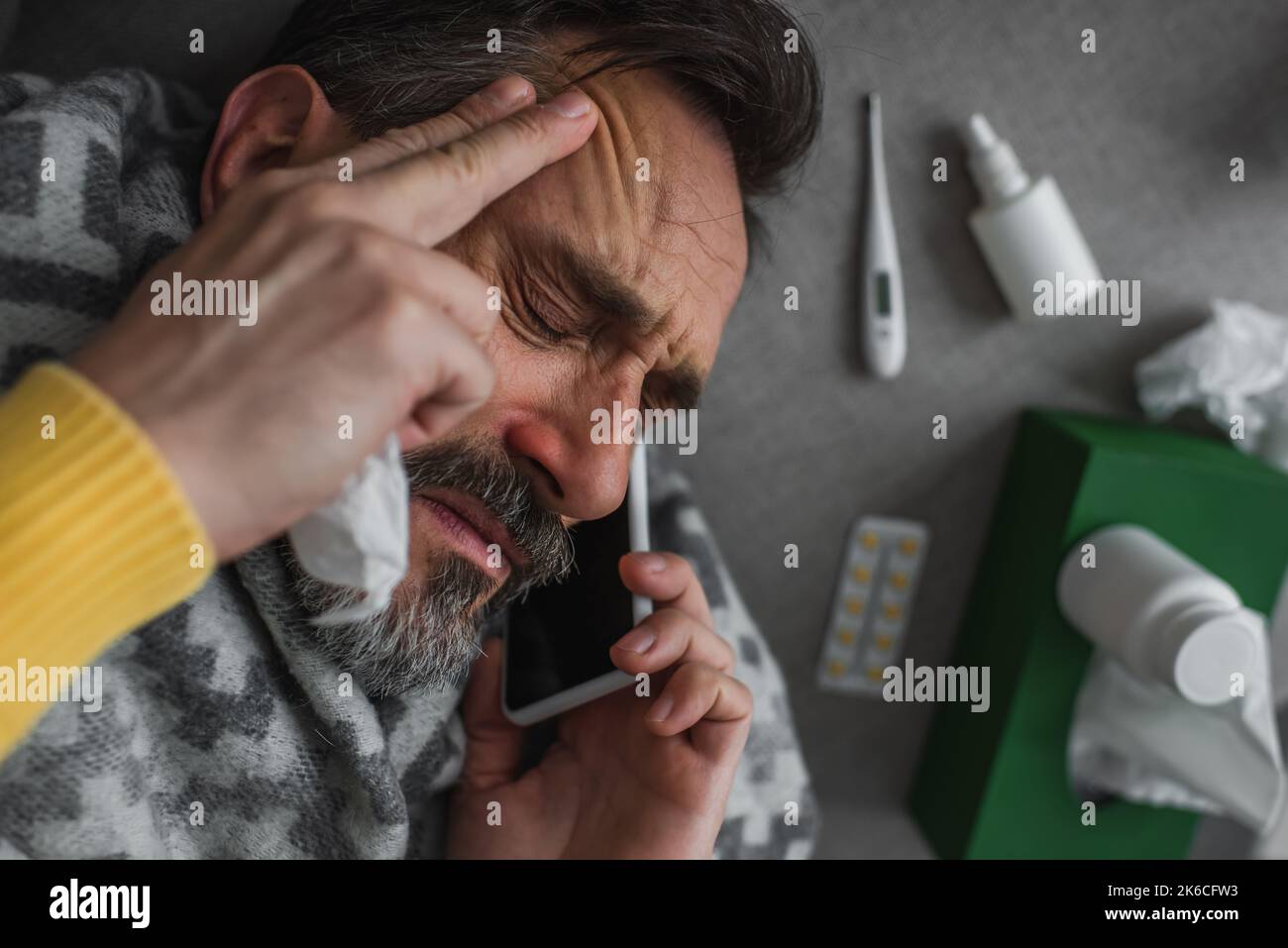 top view of sick man suffering from fever and headache while calling on ...