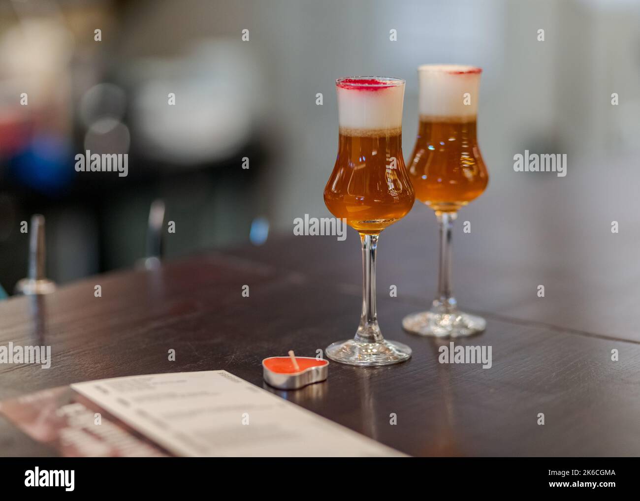 Cocktail drink shots, red heart candle, menu on table. Blurred Stock ...