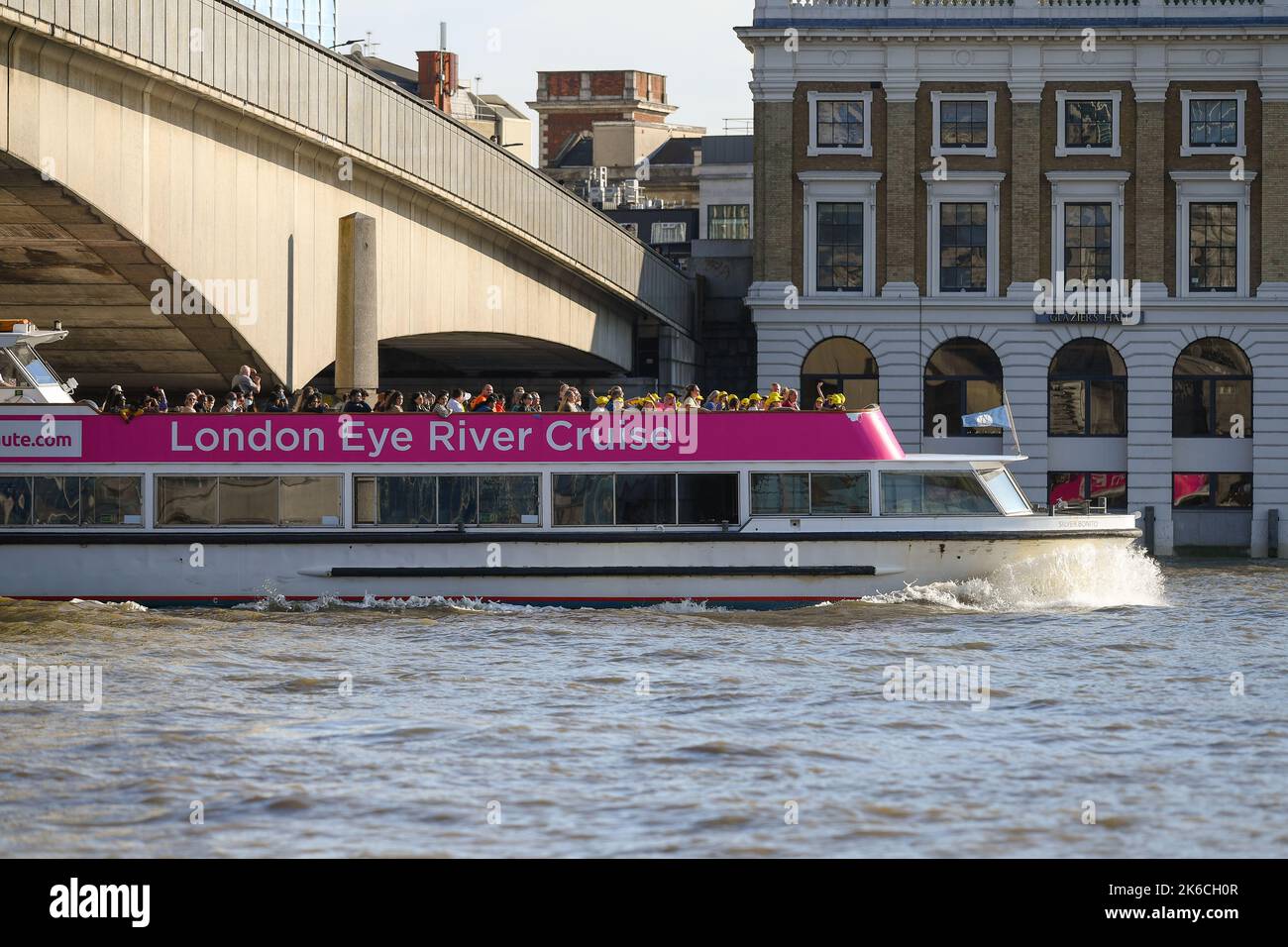 The London Eye river cruise boat travels down the Thames under London ...