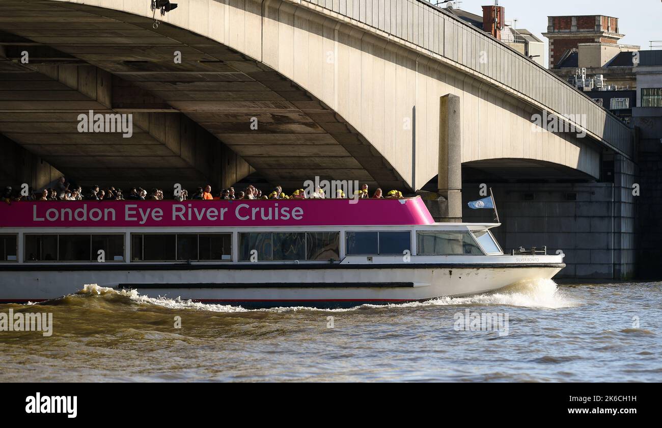The London Eye river cruise boat travels down the Thames under London ...