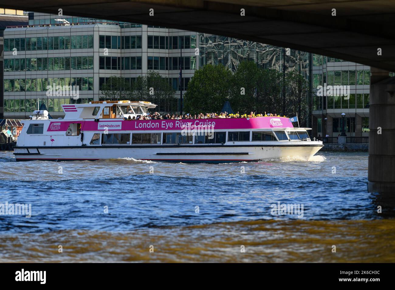 The London Eye river cruise boat travels down the Thames under London ...