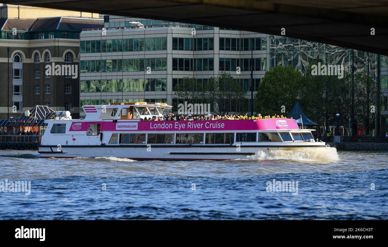 The London Eye river cruise boat travels down the Thames under London ...