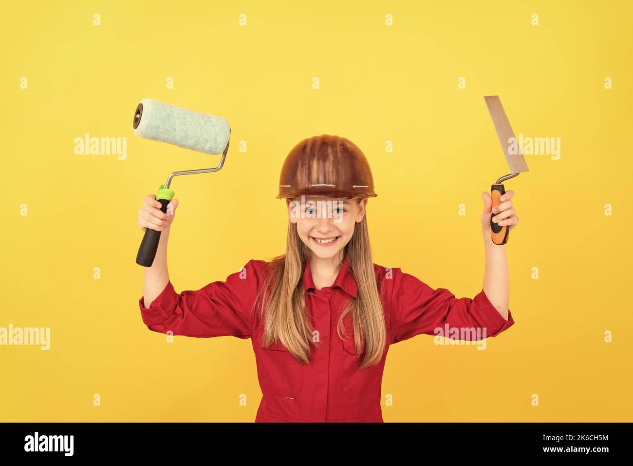 glad teen child in builder hard hat with paint roller and spatula on ...