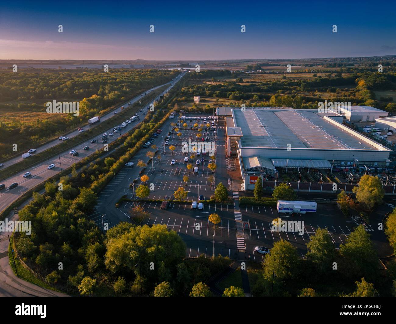 An aerial view of a road and supermarket with car park, near the nature ...