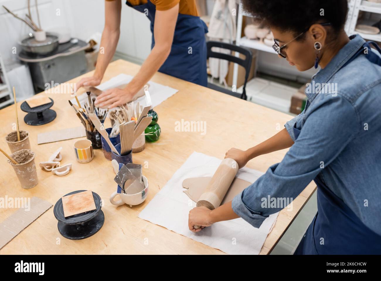 high angle view of african american woman in eyeglasses modeling clay ...