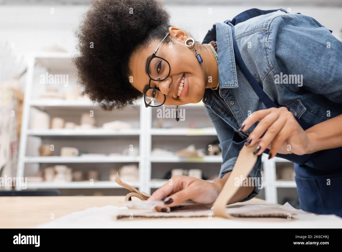 happy african american woman in eyeglasses tearing carton during ...