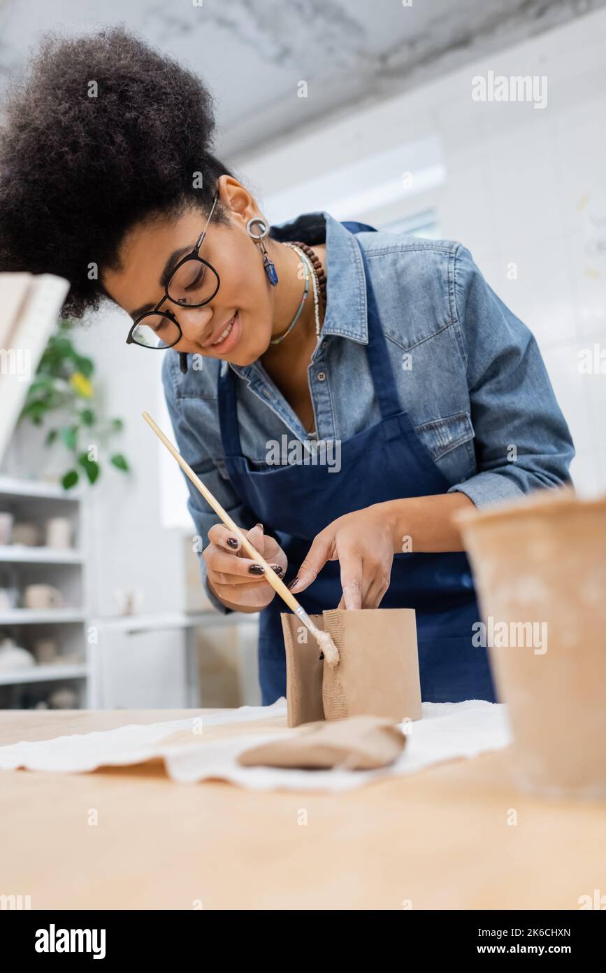 happy african american woman in apron holding shaper while modeling ...