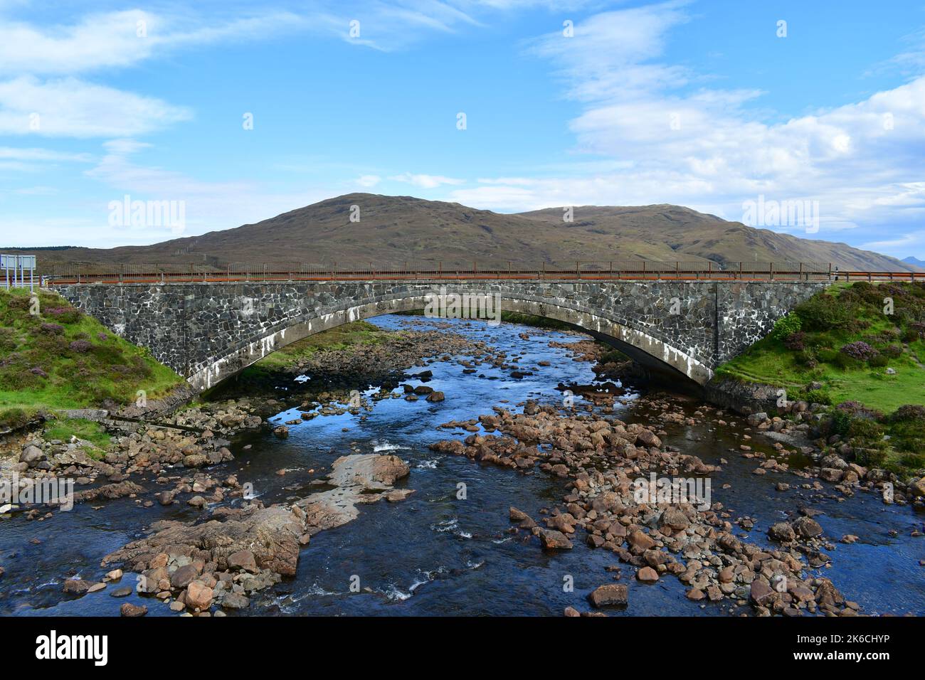 A beautiful shot of a bridge with a rocky river underneath on mountains ...