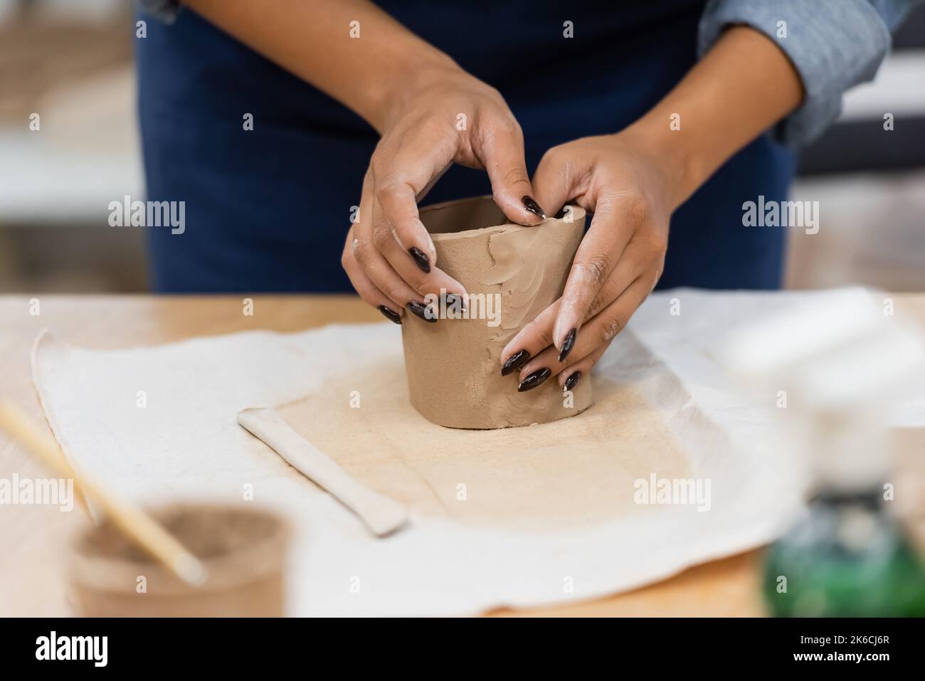 partial view african american woman with manicure shaping clay during ...