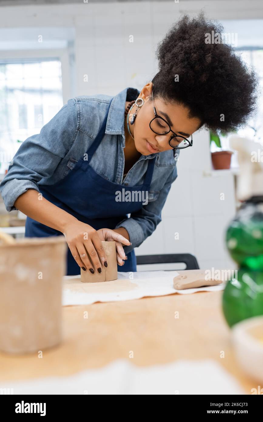 young african american woman in apron modeling clay piece during ...