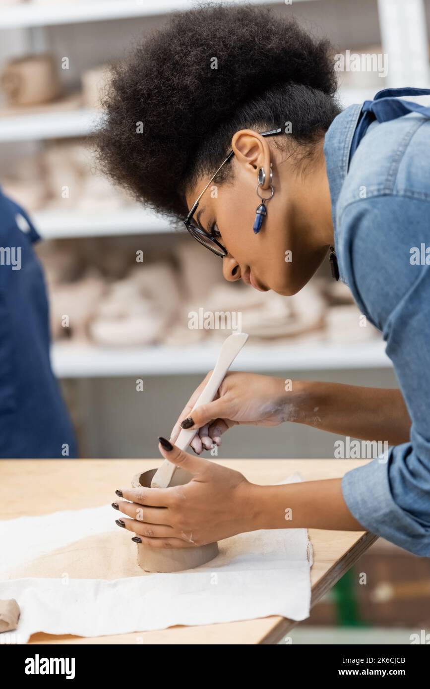 curly african american woman in eyeglasses holding shaper while ...