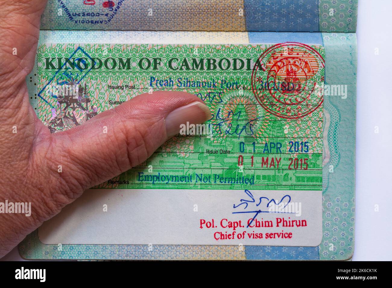 Hand holding open passport with Kingdom of Cambodia Visa in British ...