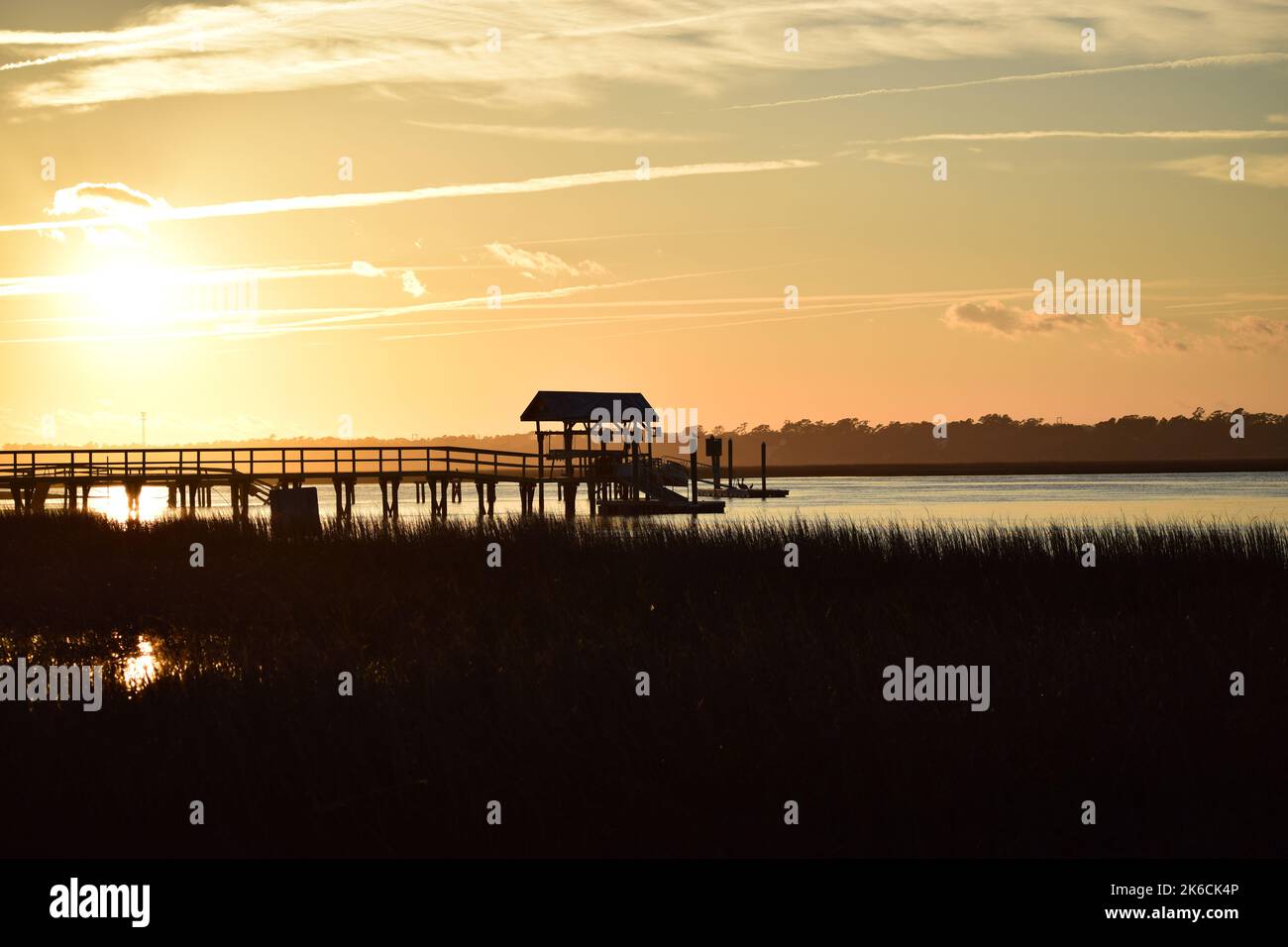 Beautiful sunset golden hour walking on the dock through the marsh and ...