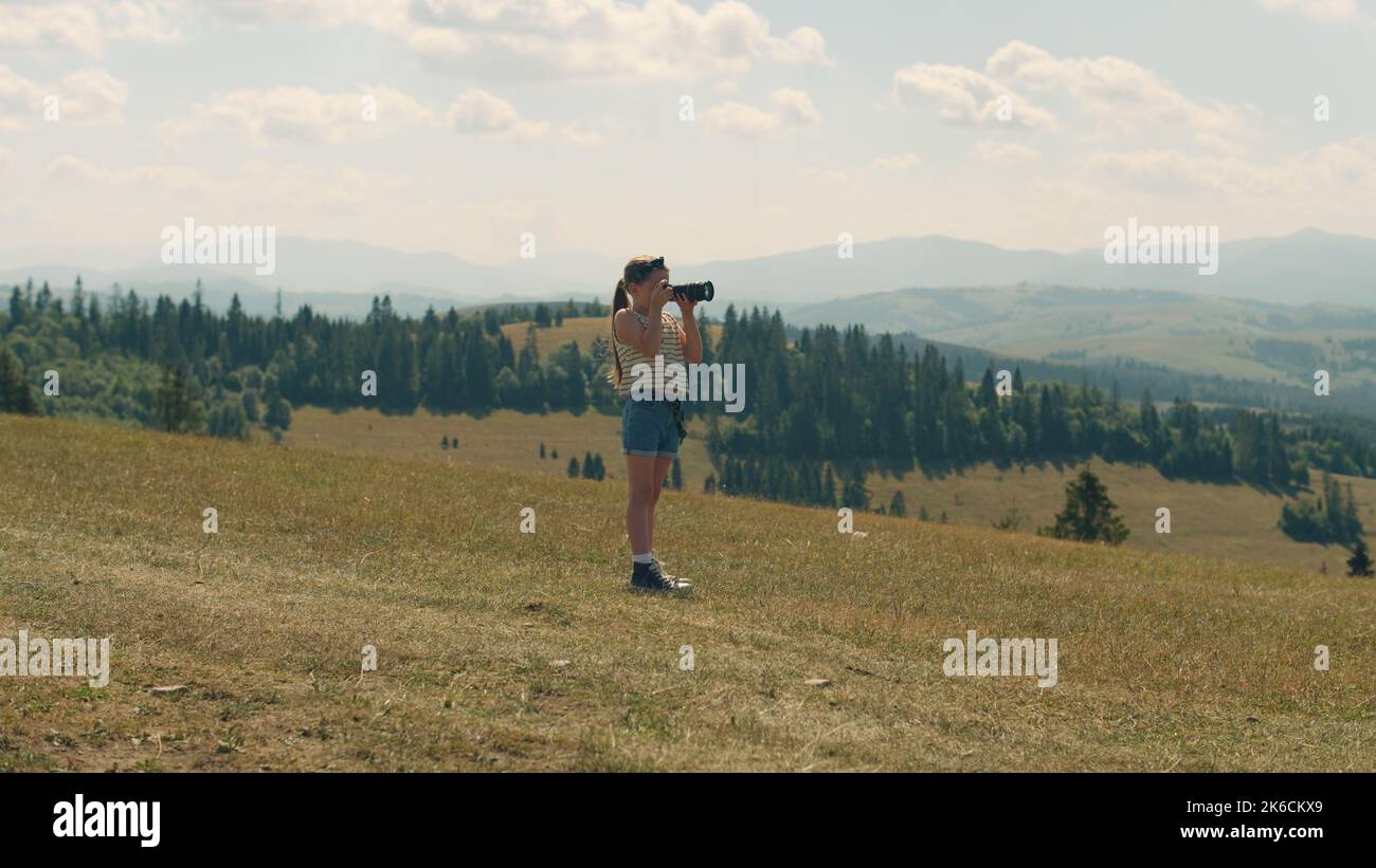 Young photographer shooting landscape on beautifull green hillway, taking pictures of nature ...