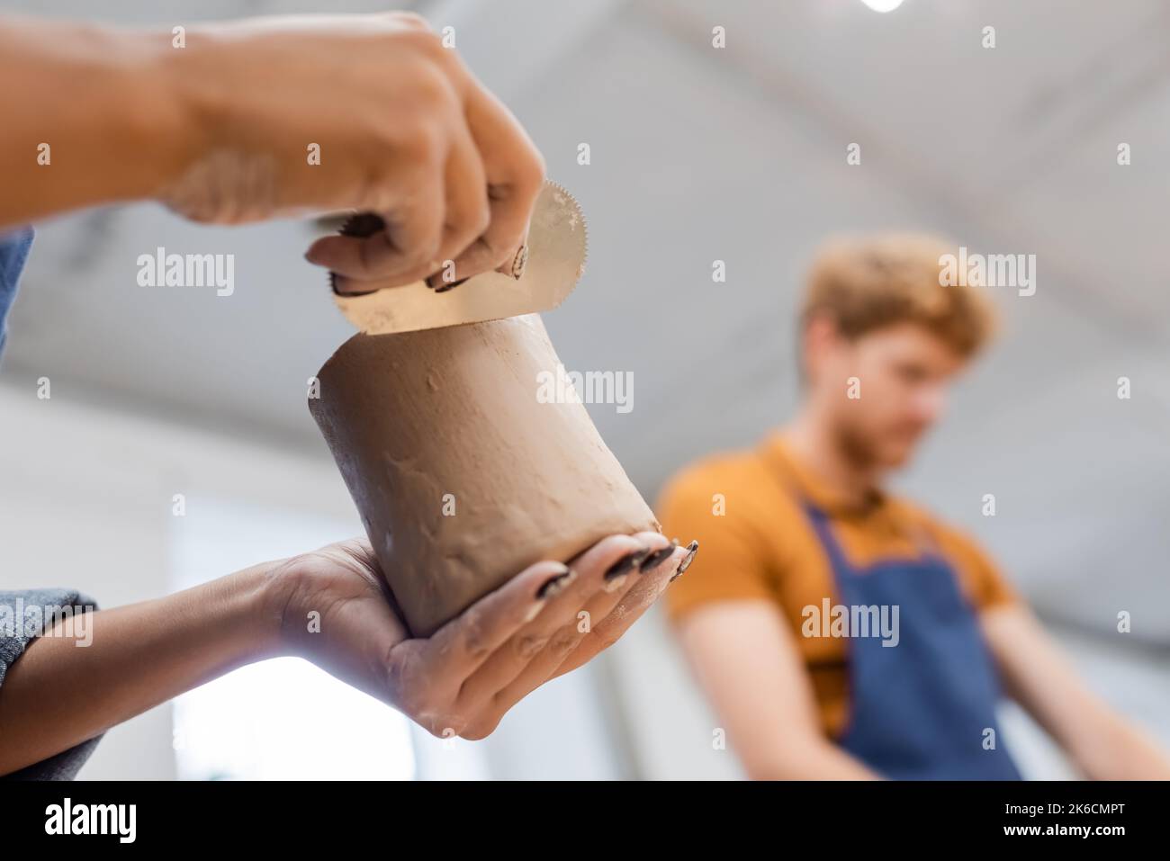 African american woman making clay cup with steel scraper near blurred ...