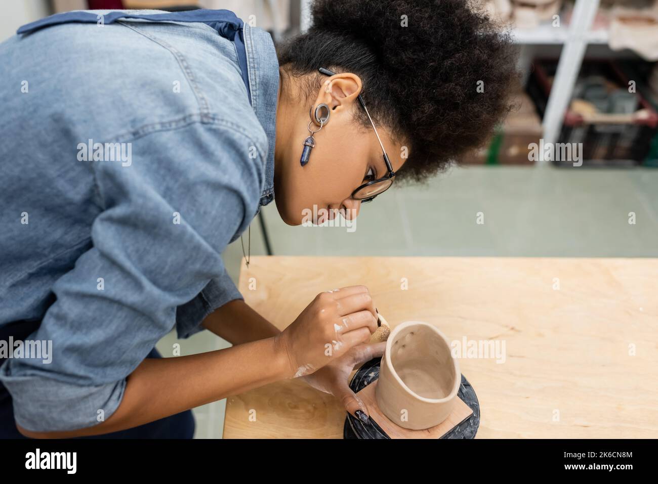 Side view of african american artisan forming ceramic product in ...