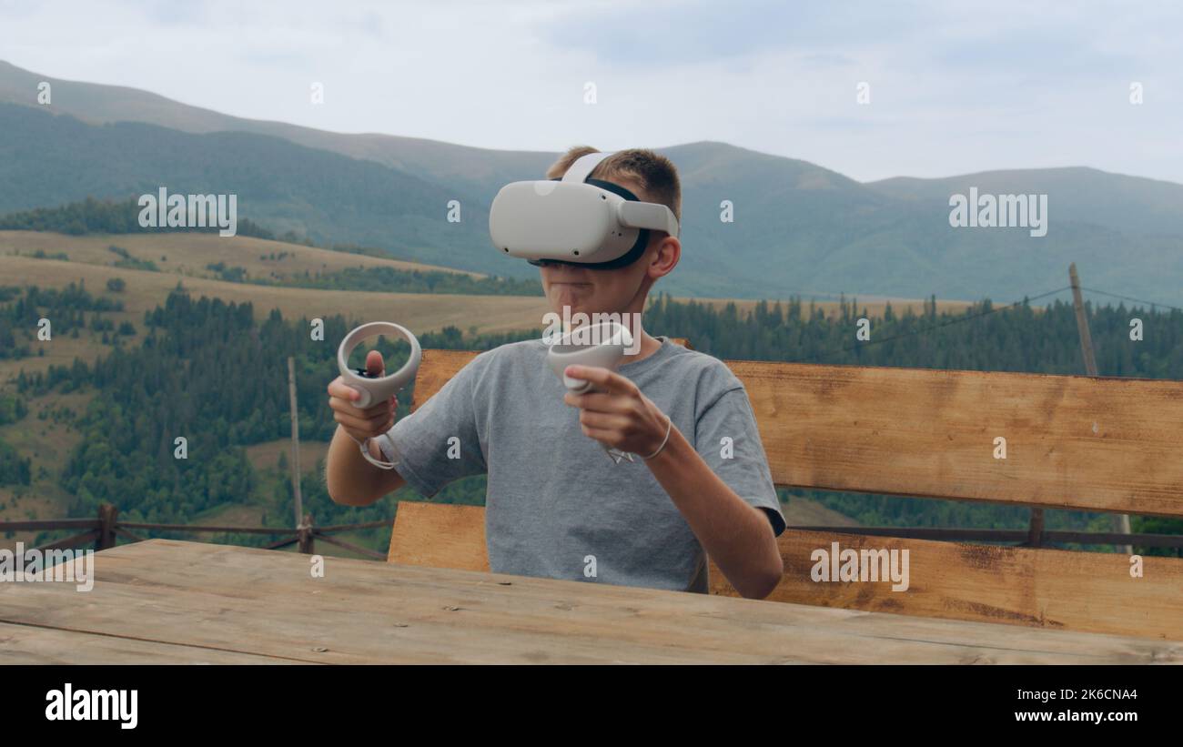 Young guy playing augmented reality games on nature, sitting on wooden ...